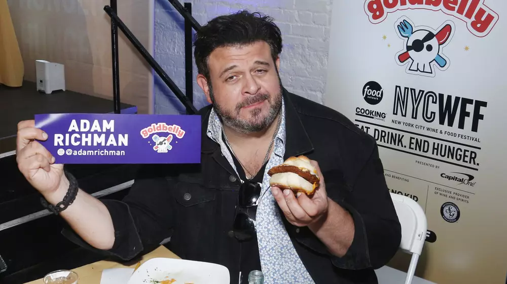 Adam Richman dari Man v. Makanan memegang burger