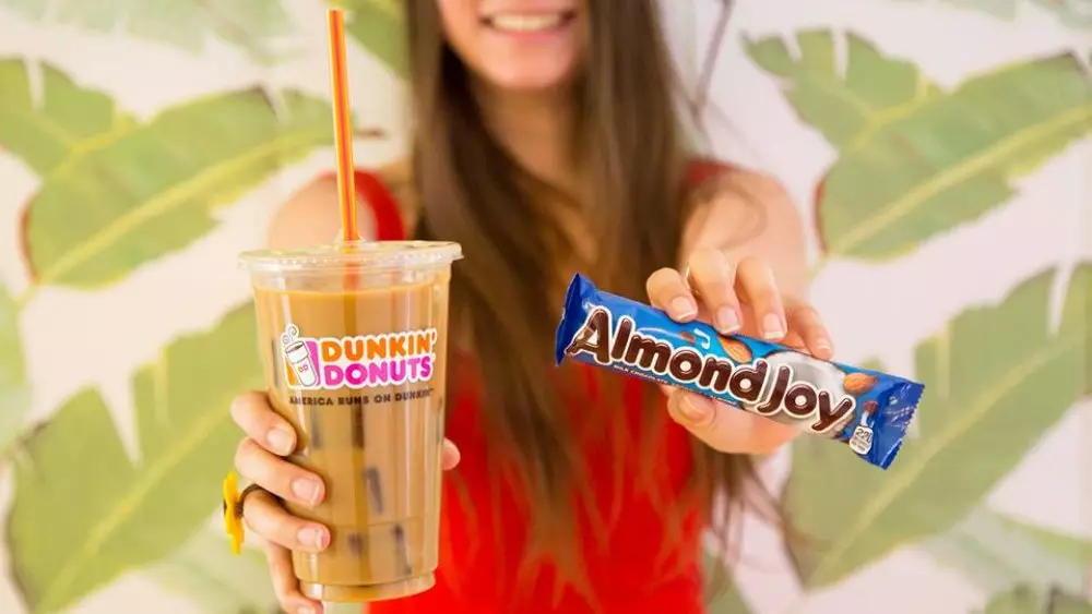 donna che tiene in mano il caffè freddo di Dunkin' Donuts e la barretta di cioccolato Almond Joy