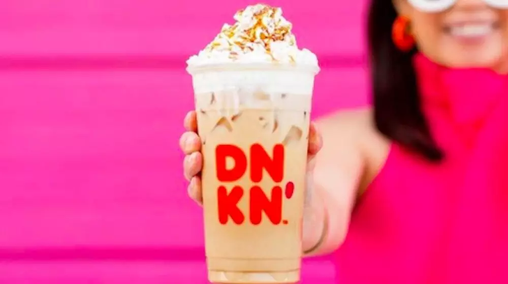 Donna che mantiene Dunkin' Donuts caffè freddo con panna montata