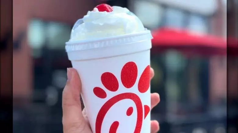 O persoană care ține în mână un milkshake Chick-fil-A