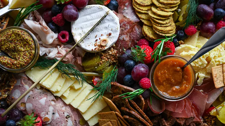 буйны план закускі з розным мясам, сырамі, садавінай і крекерамі, а таксама невялікімі шклянымі каструлямі з крупяністай гарчыцай і апельсінавай садавінай