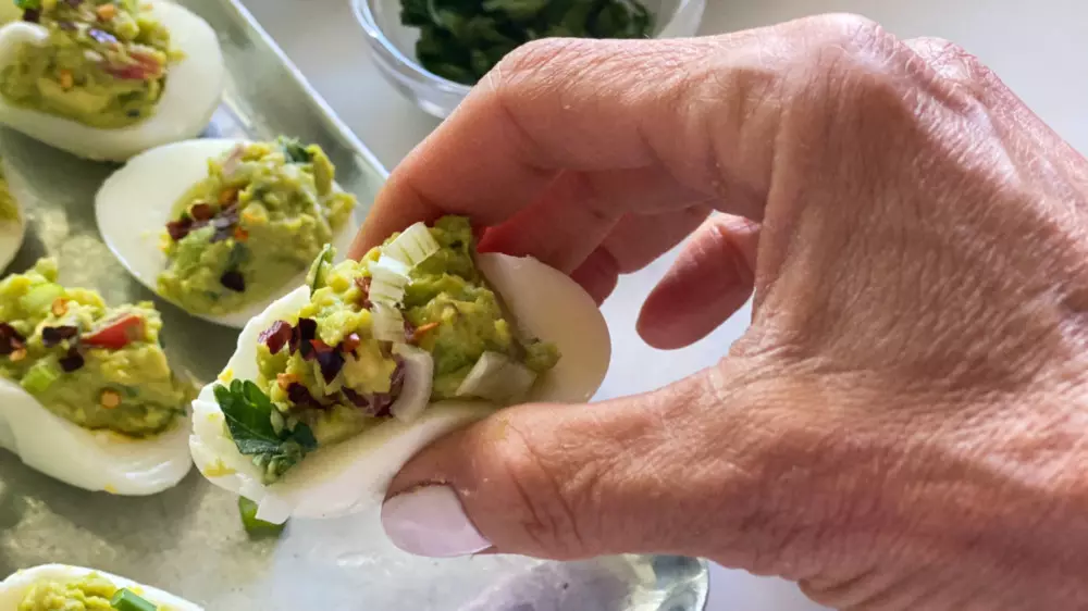 sosteniendo huevos rellenos de guacamole