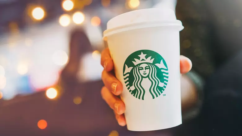 Jinek fincana qehweyê ya Starbucks di destê xwe de digire