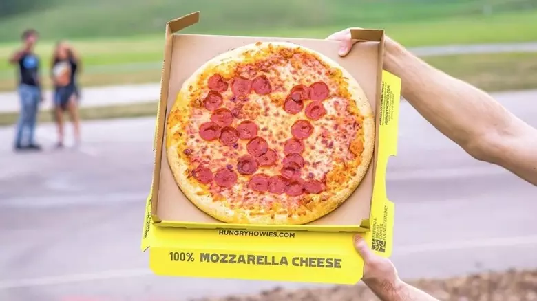 Hände halten eine Schachtel mit Hungry Howies Pizza hoch