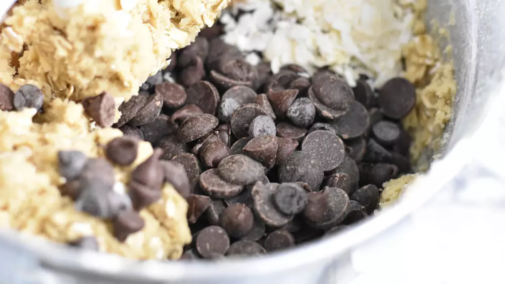 chips de chocolate, copos de coco e noces picadas na masa do recipiente