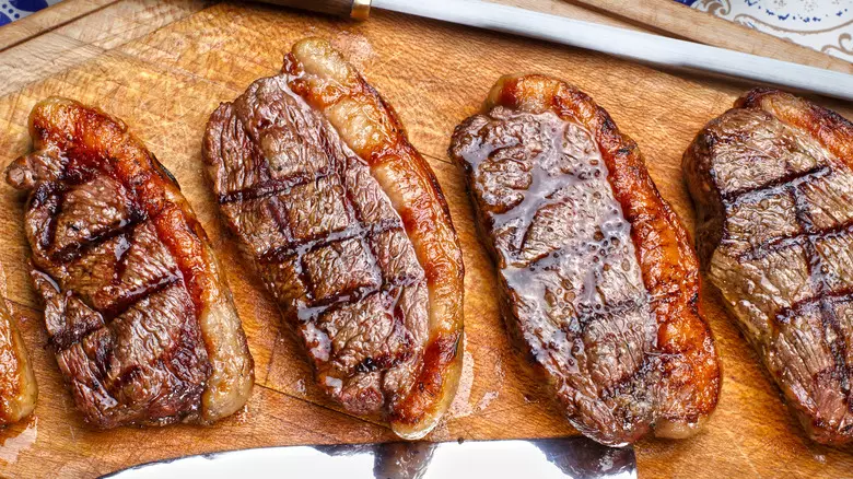 Fjouwer fatty steaks op in snijplank