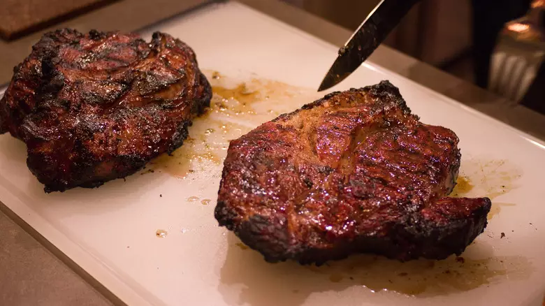 Dalawang steak sa isang cutting board na may kutsilyo.