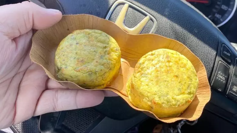 Een deen Starbucks Kale a Mushroom Egg Bites am Auto hält