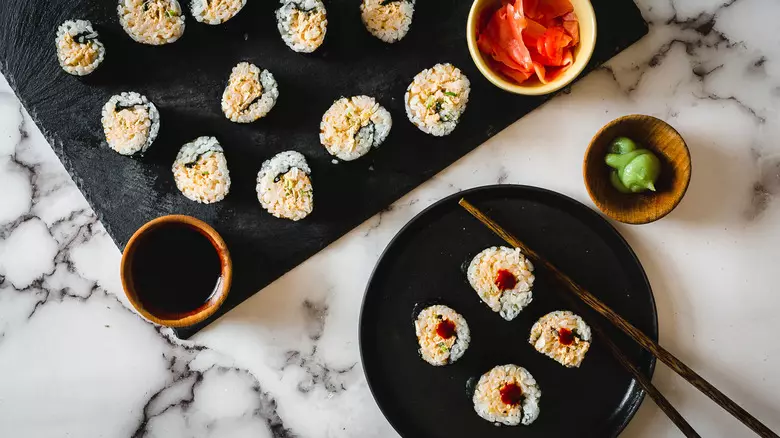 sushi në pjata për servirje me wasabi, xhenxhefil dhe shkopinj