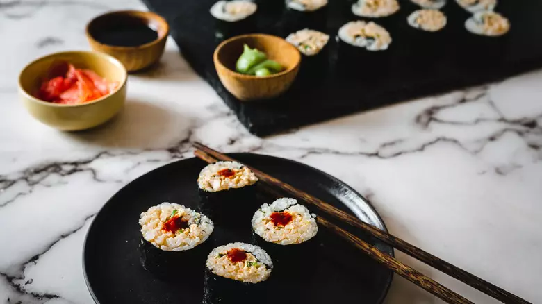 empat keping sushi di atas pinggan dengan penyepit, wasabi dan halia