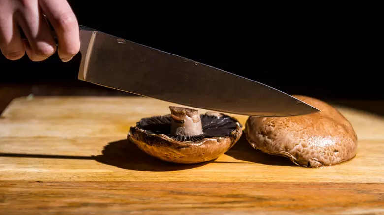 Een chef-kok die portobello-champignons snijdt