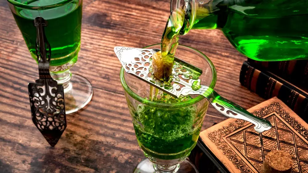 Absinthe word oor 'n suikerblokkie in 'n glas gegooi