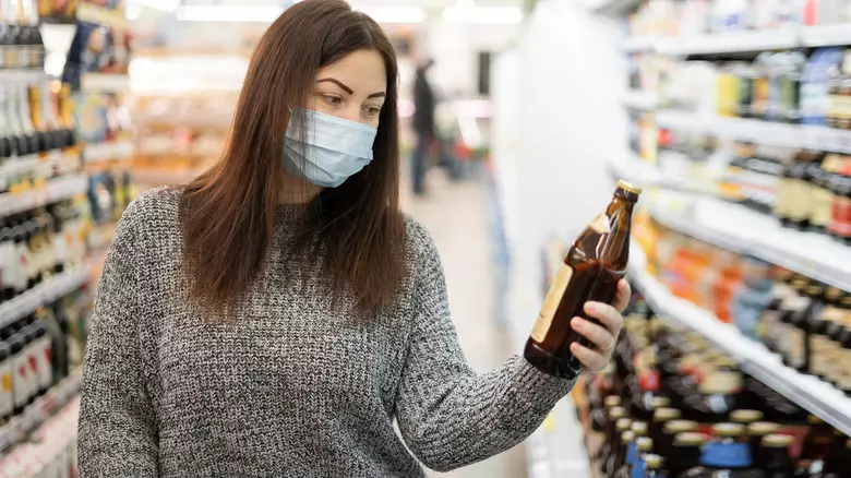 Uma mulher mascarada considerando uma cerveja