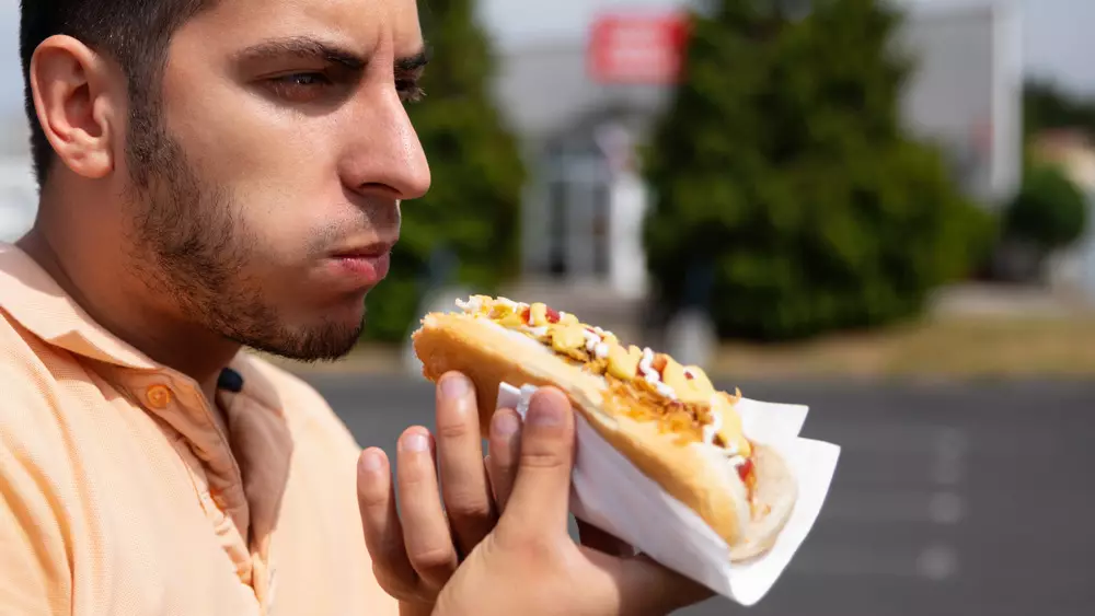 Un home comendo un cachorro quente