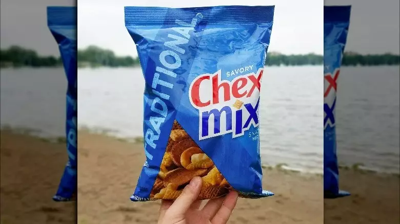 Keegi hoiab järve ääres traditsioonilise Chex Mix'i kotti käes