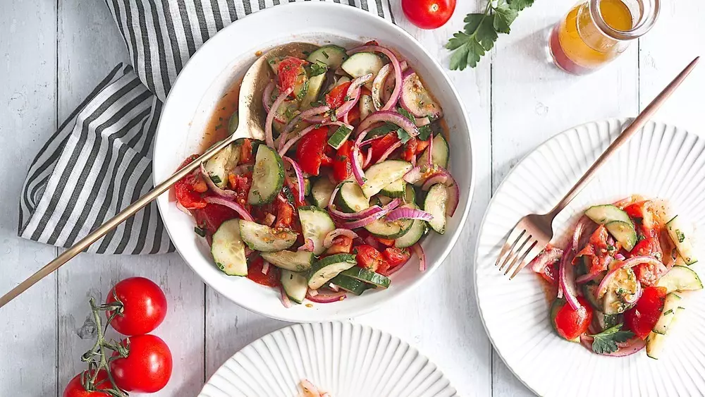 Agurk tomatsalat i en bolle med gafler og servietter