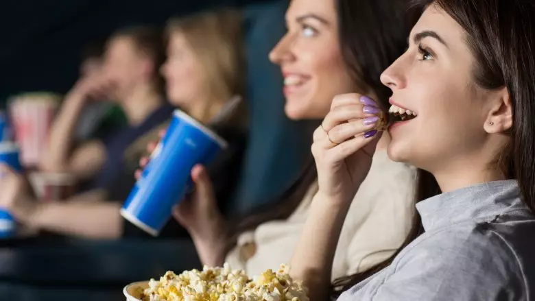 Wanita di bioskop makan popcorn