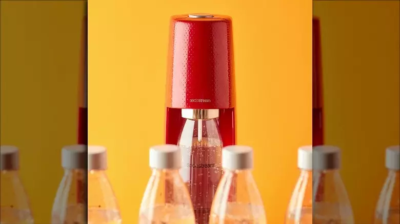 Kırmızı bir SodaStream etrafında şişeler