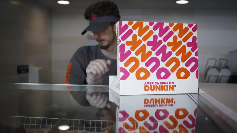 Zaposlenik popunjava otvorenu kutiju Dunkin'a