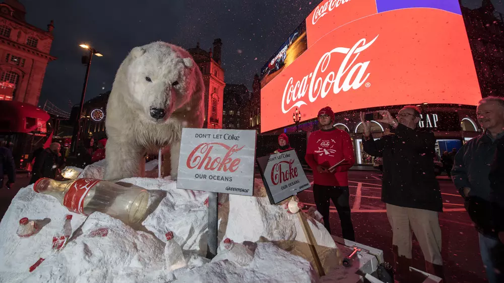 Los activistas de Greenpeace en Londres se manifiestan con una escena construida en la que un oso polar considera existencialmente lo maravilloso que es que su vida se haya rendido al progreso de Coca-Cola.