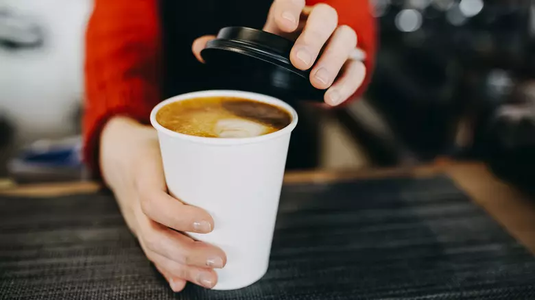 Barista con in mano un caffè da asporto