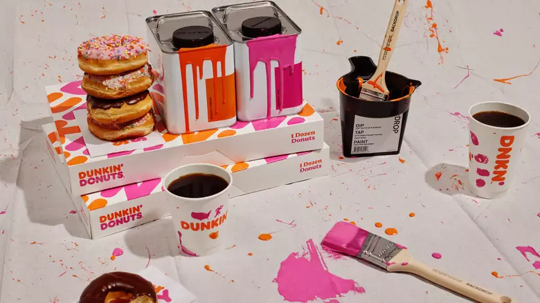Dunkin' donuts i cafè amb pintura de fons rosa i taronja i esquitxades de pintura