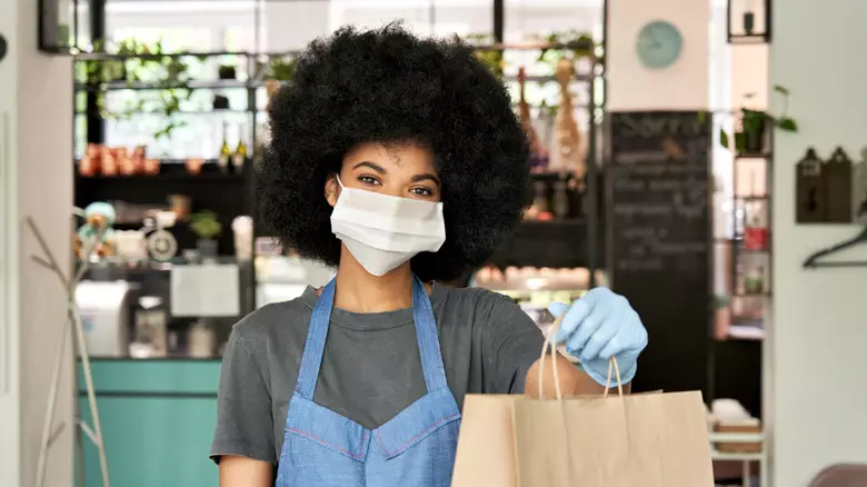 Un lavoratore mascherato consegna un sacchetto di cibo