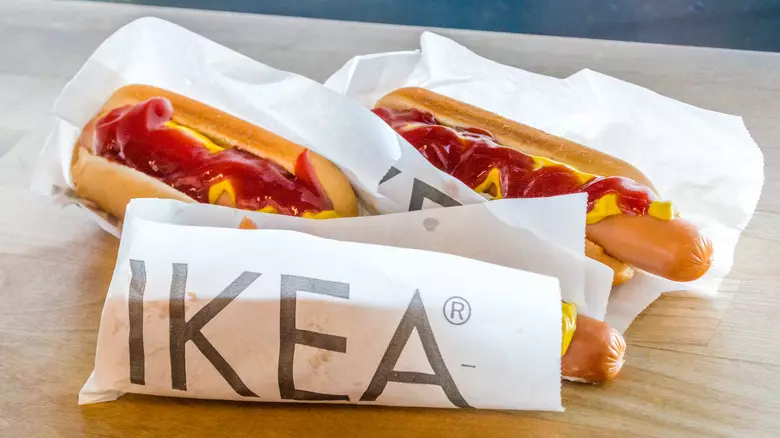 IKEA hotdogi papīra iepakojumā ar sinepēm un kečupu