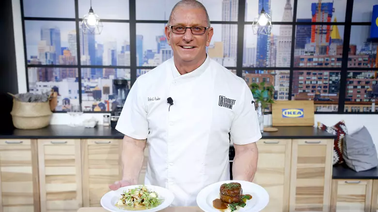 Robert Irvine szakácskabátban, tányérokat tart a kezében