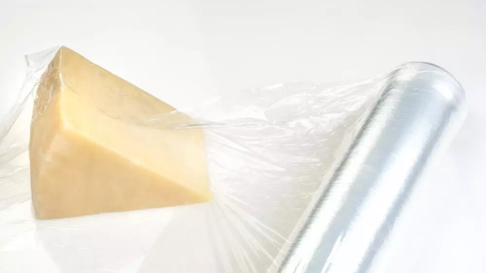 Stück Käse in Plastikfolie eingewickelt