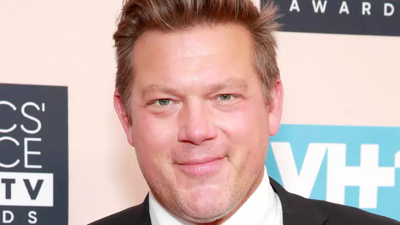 Tyler Florence draacht in pak op wite eftergrûn