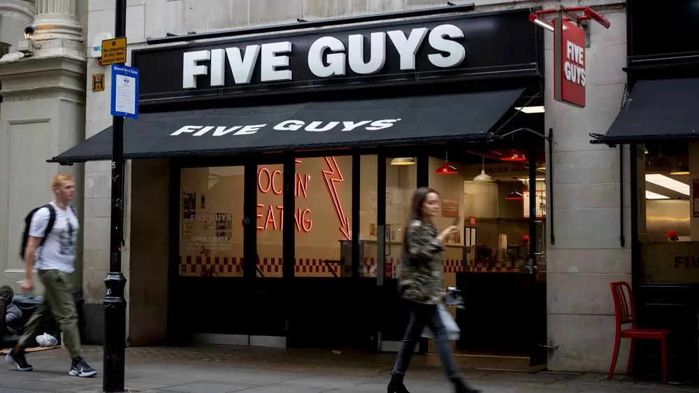 Vitrinë e Five Guys, njerëz që ecin