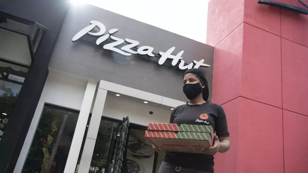 Nakatayo ang empleyado sa harap ng Pizza Hut