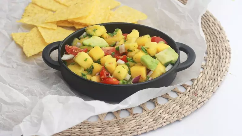 Xips de truita en un plat amb salsa de mango i mitja llima