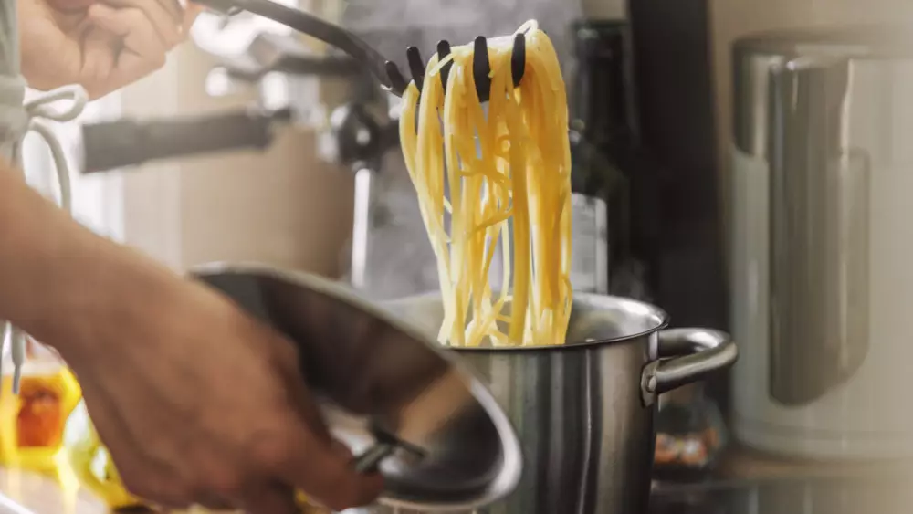 Orang yang merebus pasta dalam panci krom