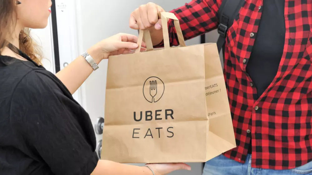 Persona che consegna una borsa Uber Eats marrone