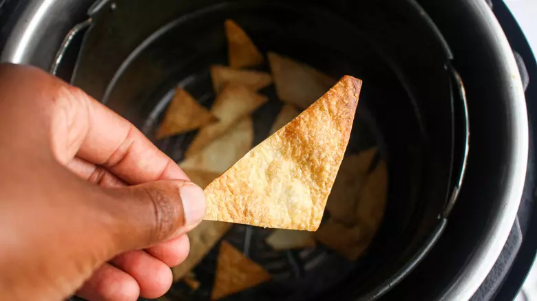 Fitues ajri me dorë që mban çip tortilla e përfunduar