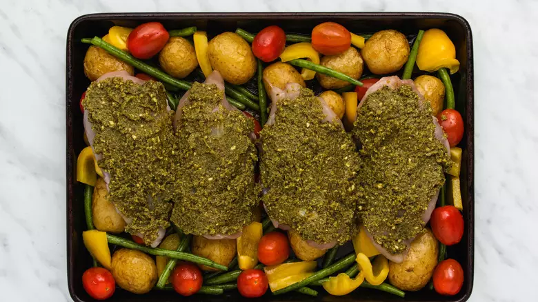 Mit Pesto bedeckte Hähnchenbrust in vorbereiteter Pfanne mit Gemüse