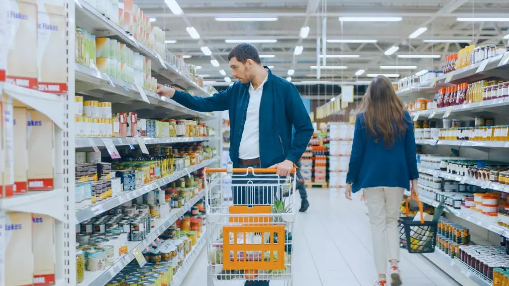 Supermerkatu batean kontserbak erosten dituen pertsona baten irudi generikoa