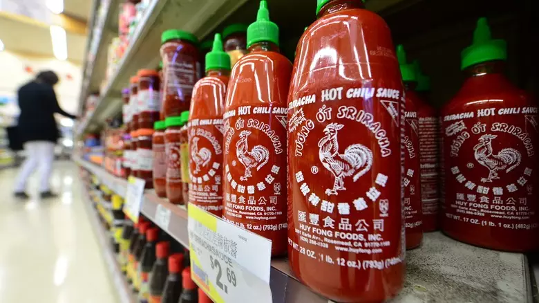 Rêzên şûşeyên Sriracha li firotanê