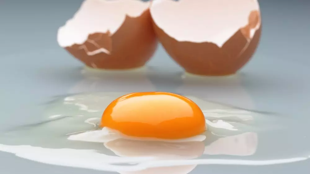 Sprukket rå egg med eggeplomme
