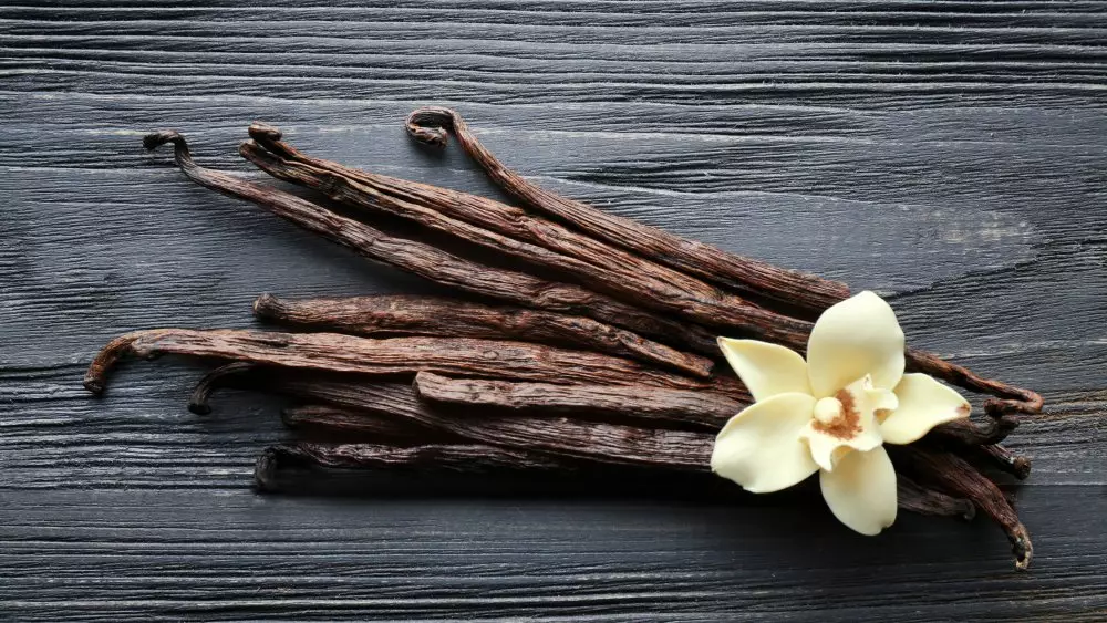 polong dan bunga vanilla bean dengan latar belakang kayu