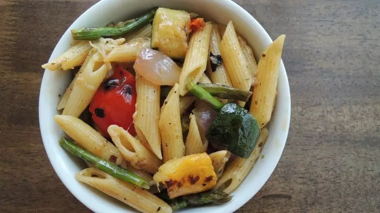 pasta dish na puno ng sariwang ani sa mangkok sa kahoy na mesa