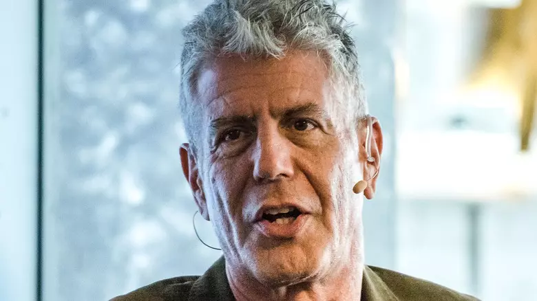 Anthony Bourdain သည် နားကြပ်ဖြင့် စကားပြောနေသည်။