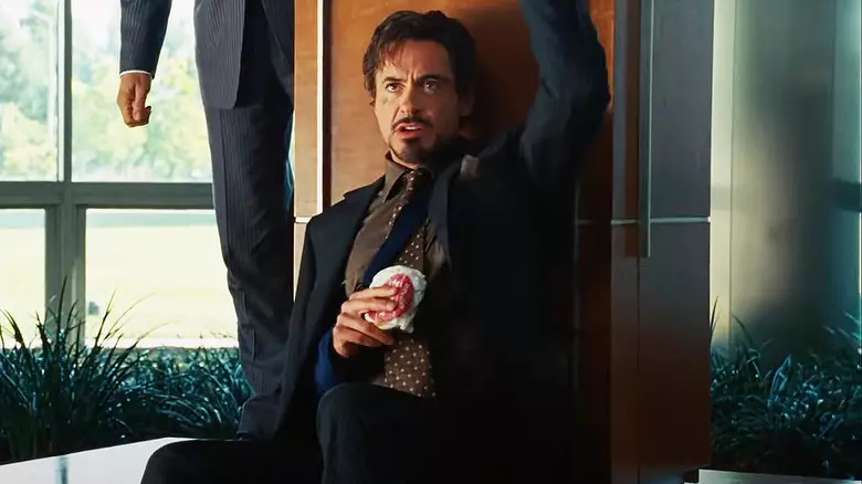 Tony Stark sosteniendo una hamburguesa con queso envuelta