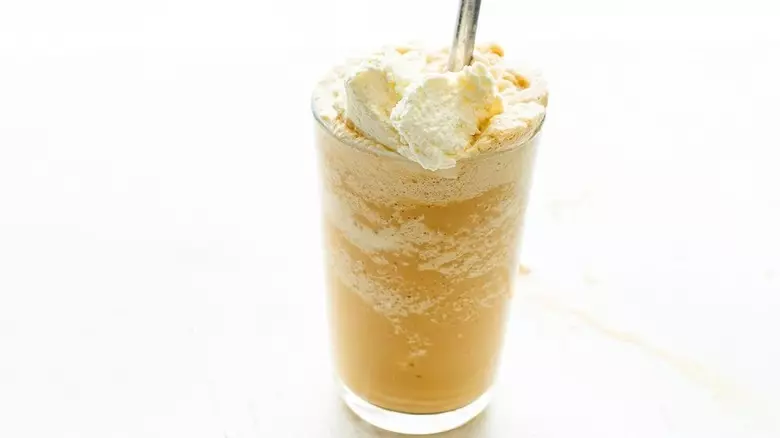 Usa ka taas nga baso sa frozen whipped coffee frappuccino nga adunay whipped cream ug usa ka straw