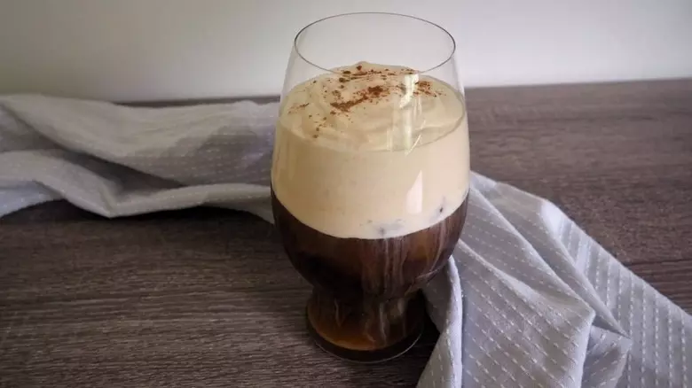 Usa ka baso nga itom nga bugnaw nga brew nga kape nga gipauna sa daghang kantidad sa whipped pumpkin-flavored foam