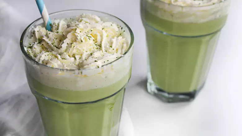 Két nagy pohár zöld fagyasztott matcha latte, tetején tejszínhabbal és szívószállal