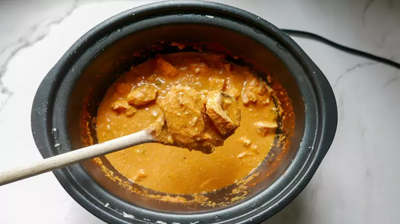 sesendok kayu kari ayam kelapa krim dengan kacang mete dalam slow cooker