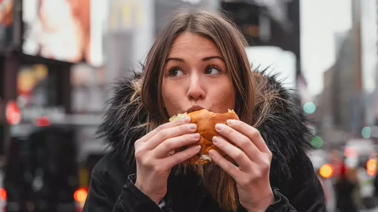 Sieviete Ņujorkā ēd burgeru